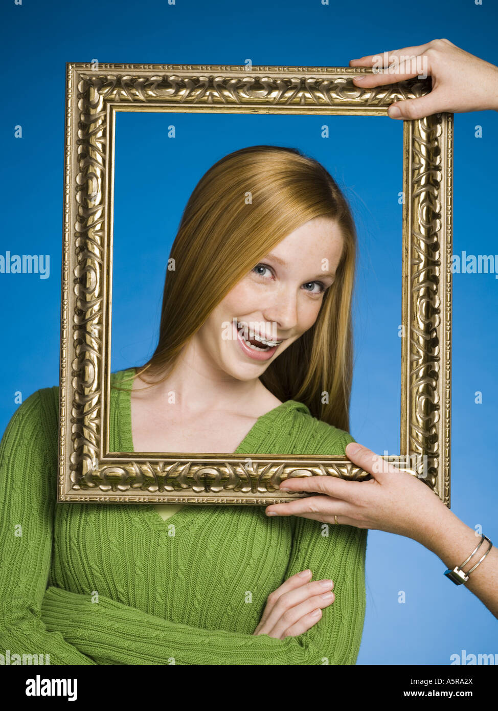 Girl looking through picture frame smiling Stock Photo - Alamy