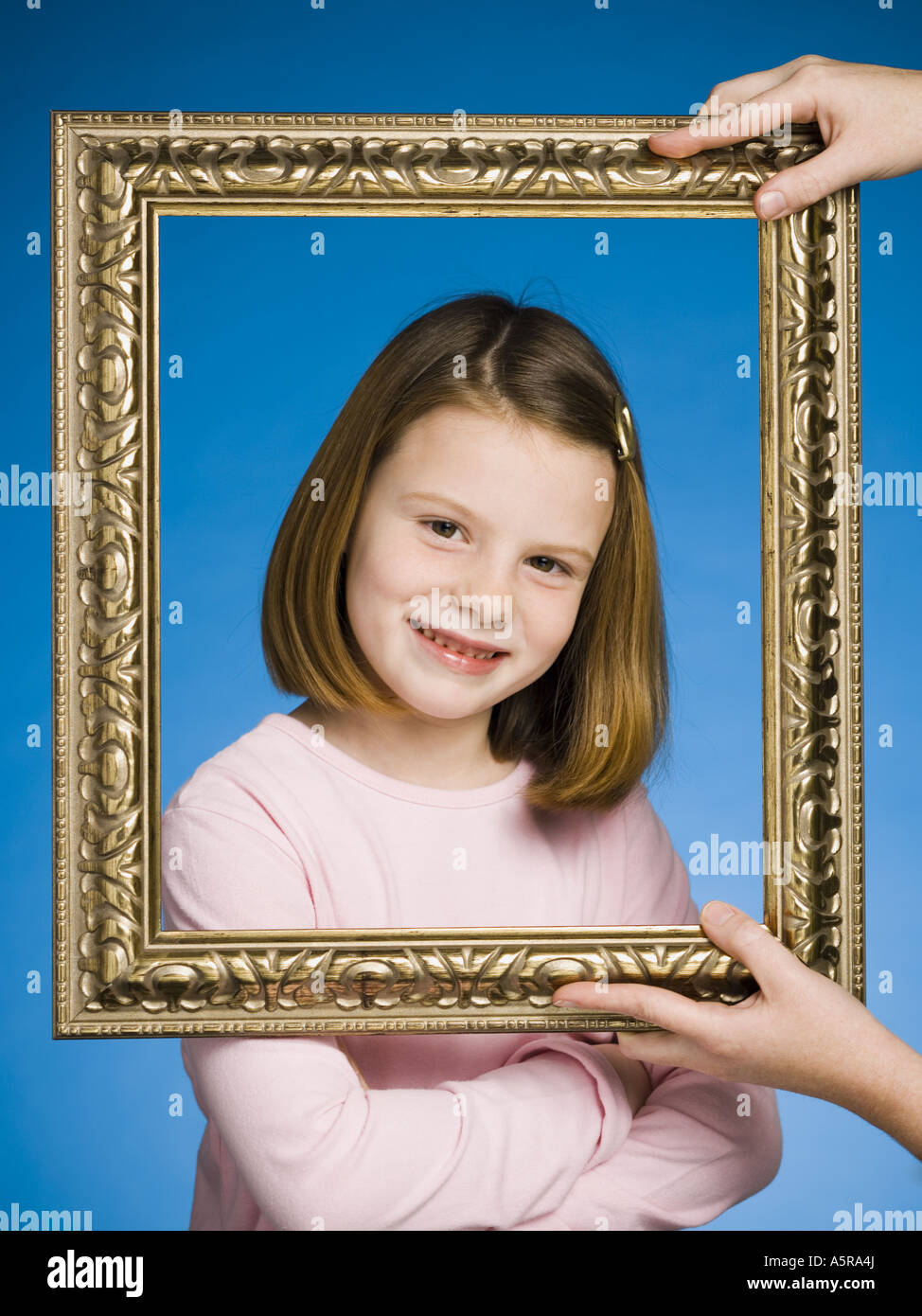 Girl looking through picture frame smiling Stock Photo - Alamy