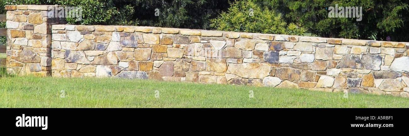 Stone rock wall landscaping fence Stock Photo - Alamy