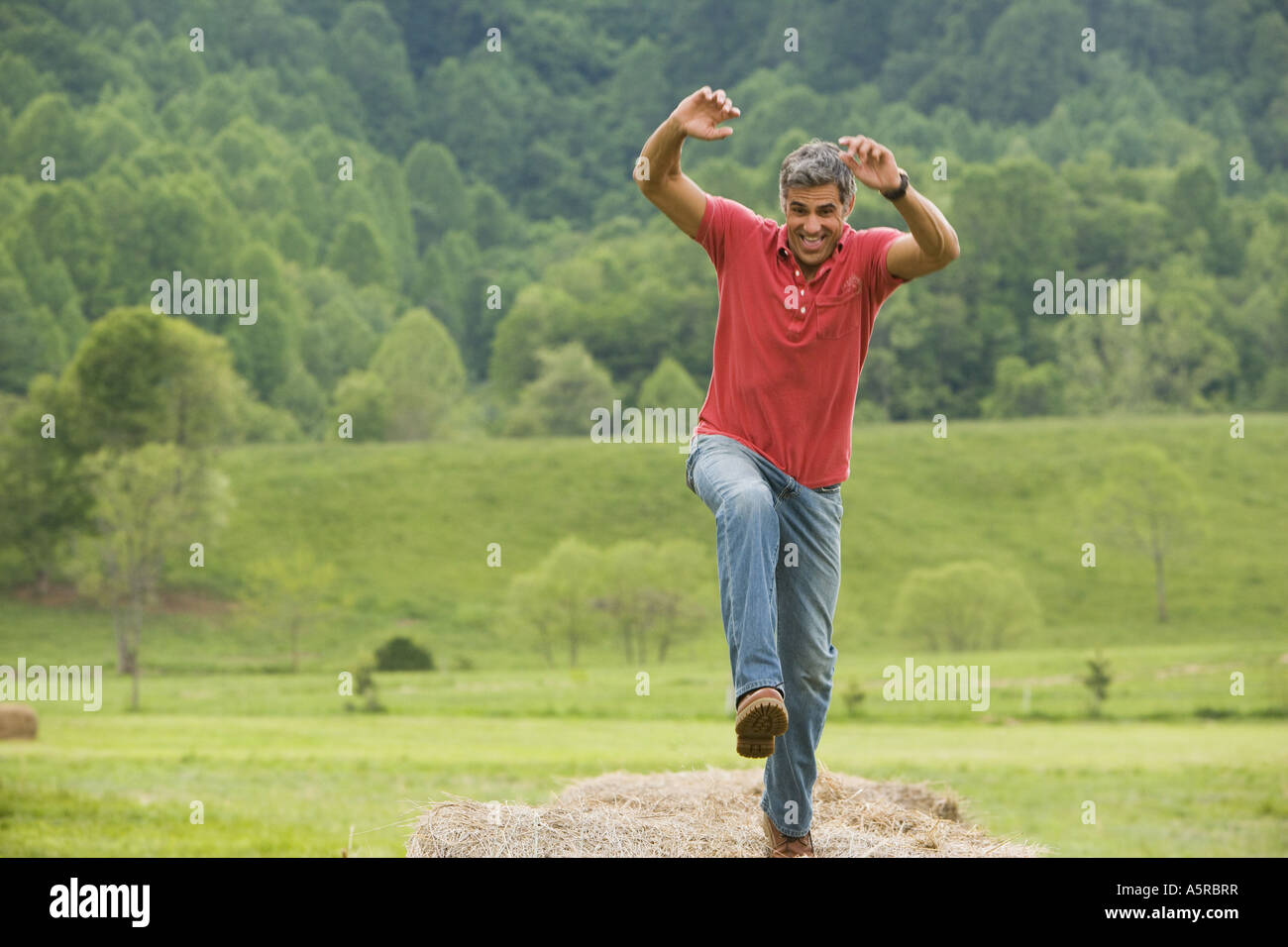 Portrait of a man jumping on a hay bale Stock Photo - Alamy