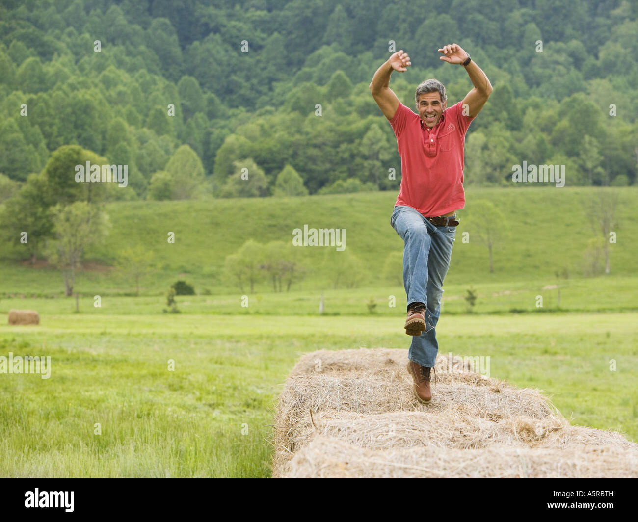 Portrait of a man jumping on a hay bale Stock Photo - Alamy