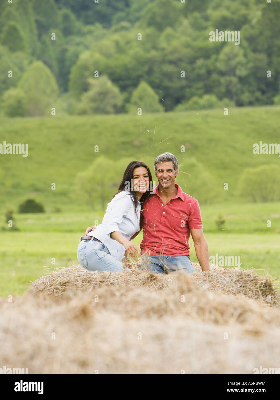man and a woman sitting on a hay bale Stock Photo - Alamy