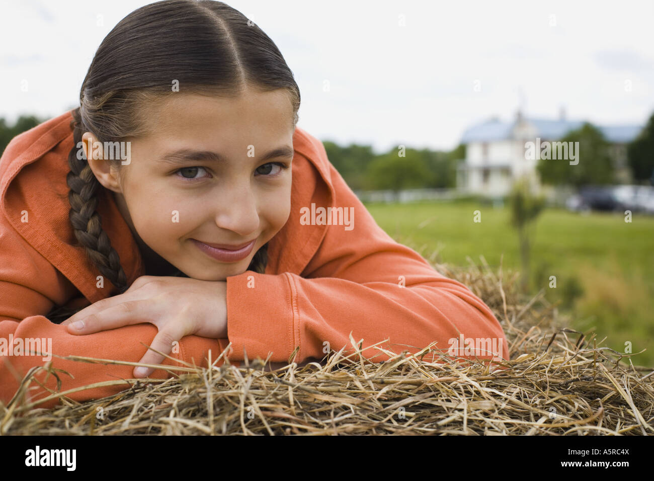 Portrait of a girl leaning over a haystack Stock Photo - Alamy