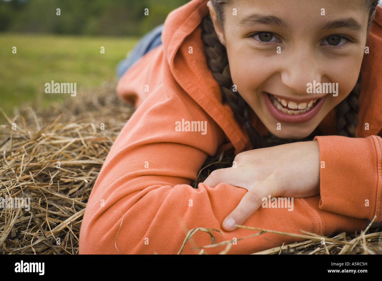 Portrait of a girl leaning over a haystack Stock Photo - Alamy