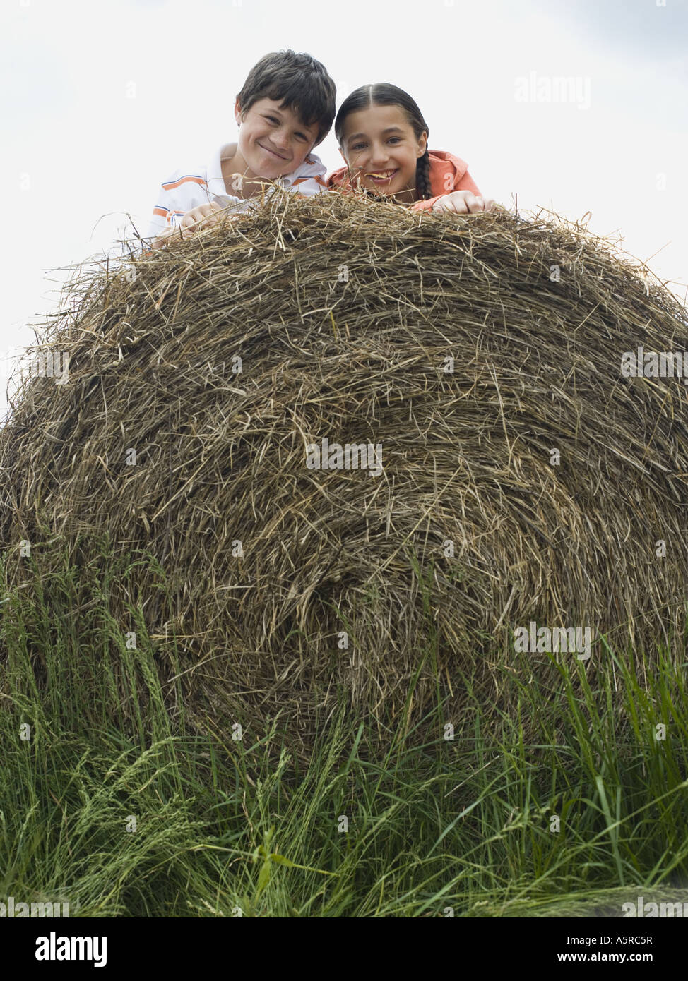 Portrait of a boy and a girl lying on top of a haystack Stock Photo - Alamy