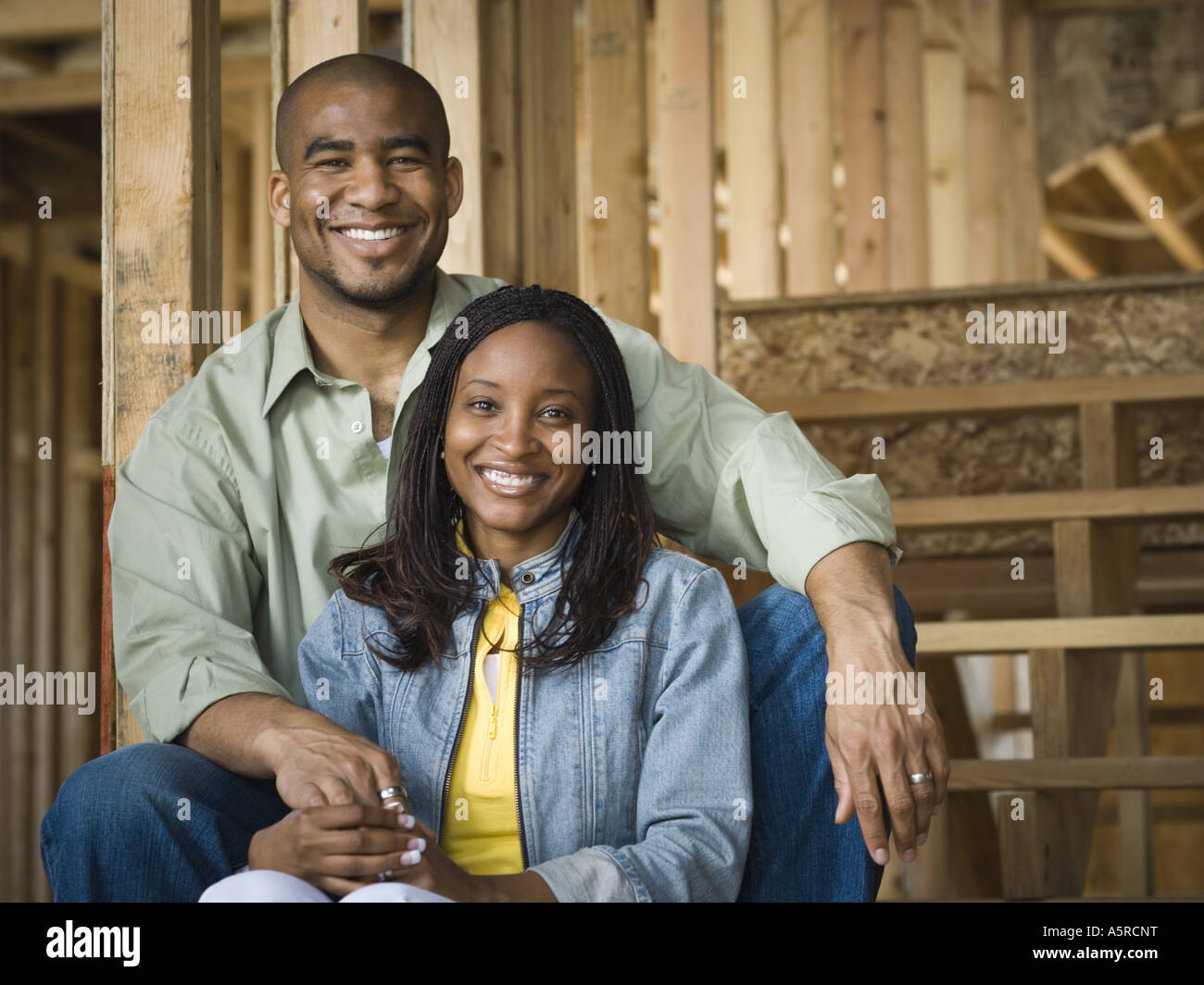 Portrait of a young couple sitting and smiling Stock Photo - Alamy