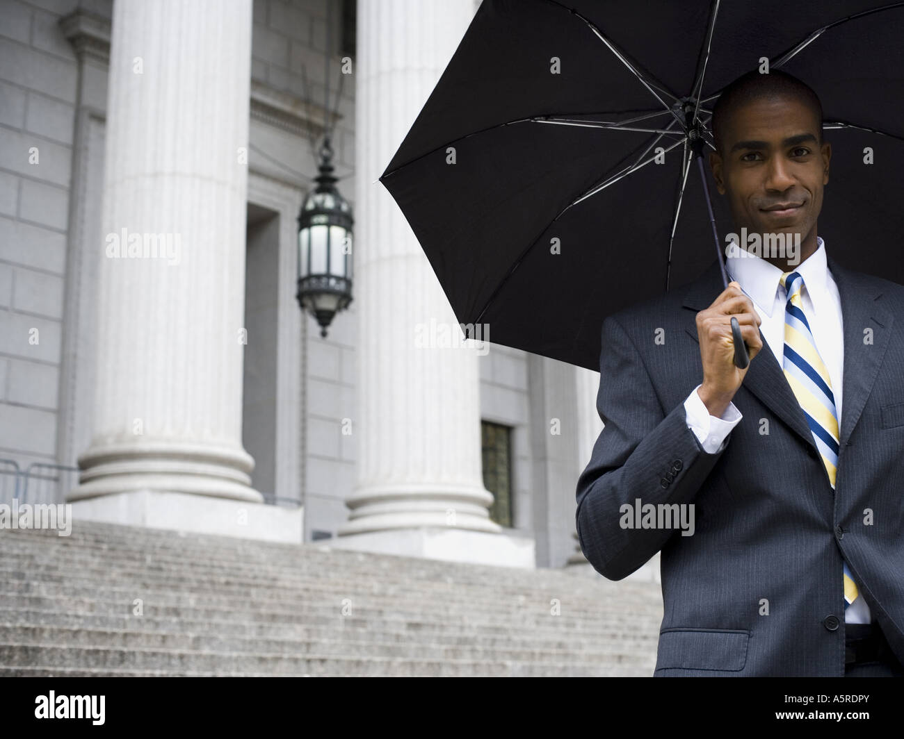 Portrait of a male lawyer standing in front of a courthouse and holding ...