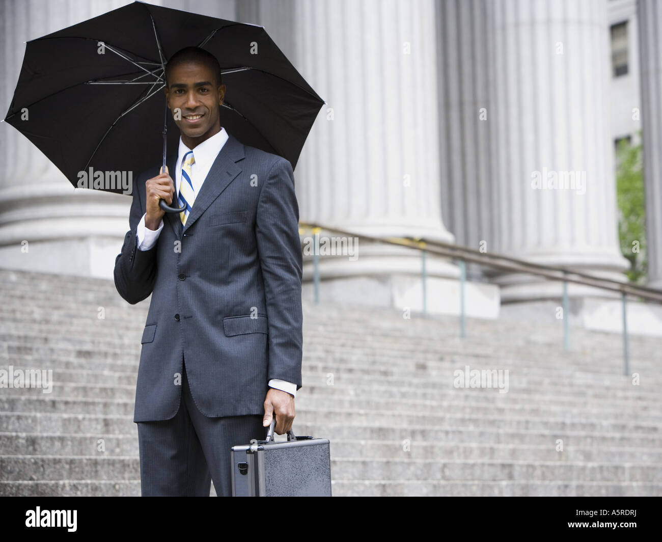 Portrait of a male lawyer standing in front of a courthouse and holding ...