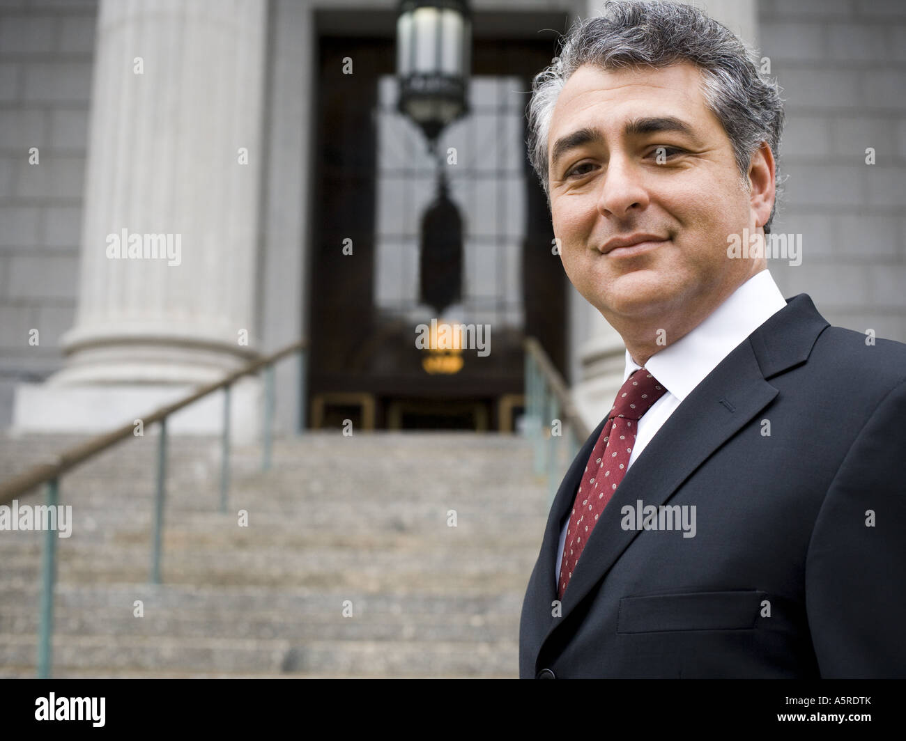 Portrait of a man standing on the steps of a courthouse and smiling ...