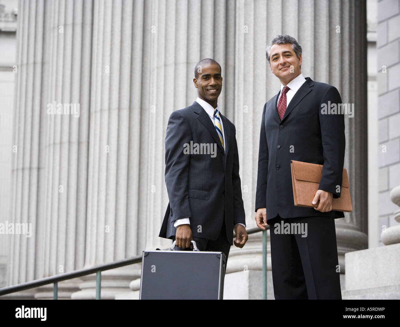 Low angle view of two men smiling and standing in front of a courthouse ...