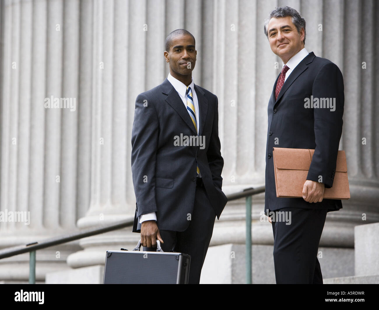 Low angle view of two men smiling and standing in front of a courthouse ...