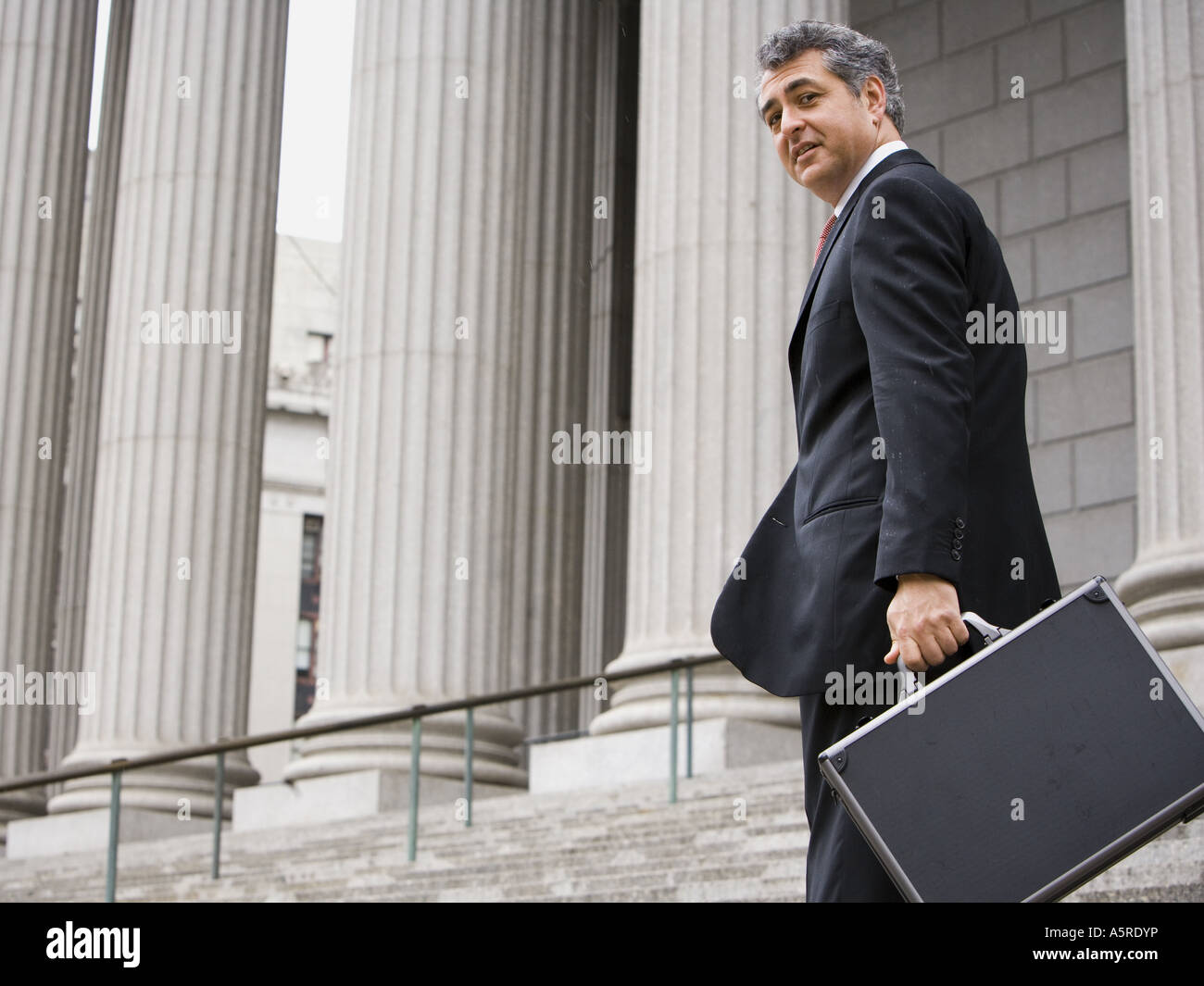 Low angle view of a male lawyer standing on the steps of a courthouse ...