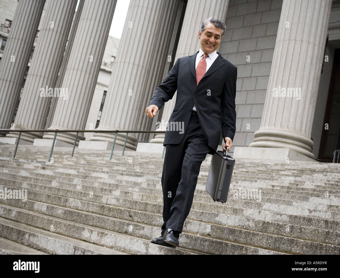 Low angle view of a male lawyer walking down the steps of a courthouse ...