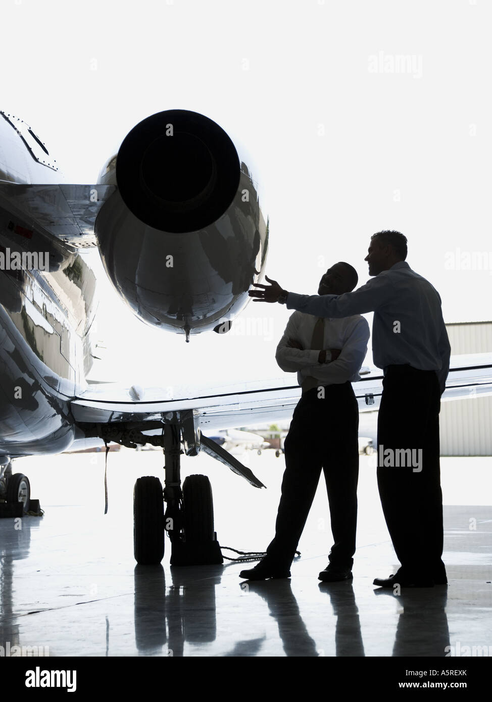Two businessmen looking at a jet engine on an airplane Stock Photo - Alamy