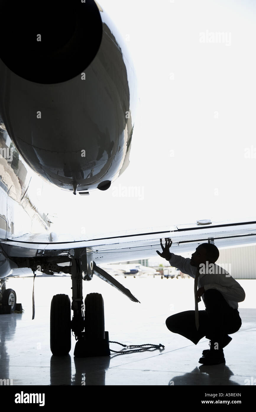 Businessman crouching and inspecting an airplane wing Stock Photo - Alamy