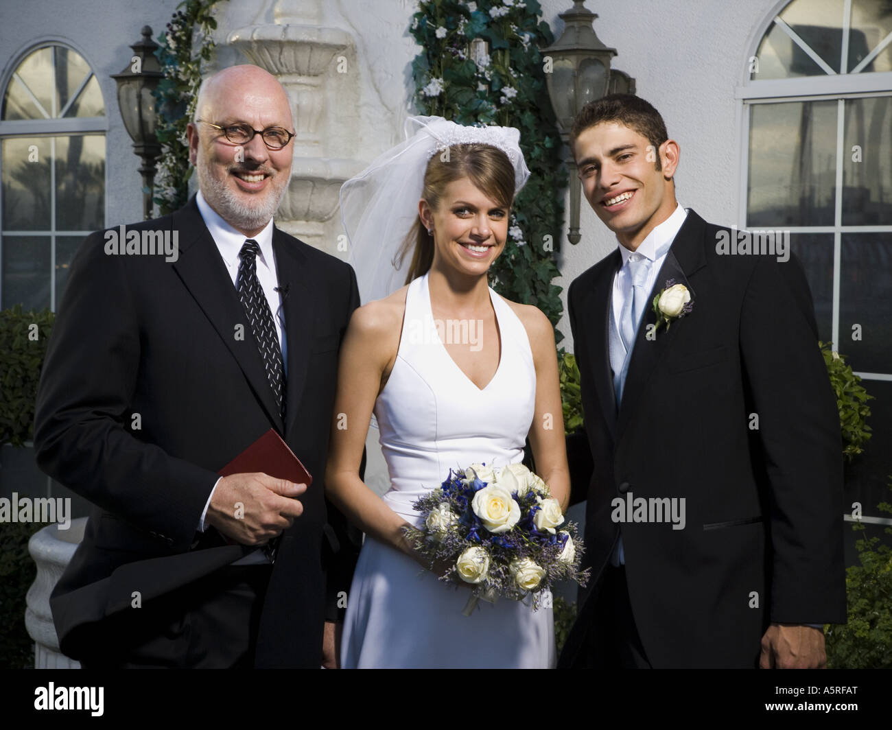 Portrait of a priest smiling with a newlywed couple in a chapel Stock ...