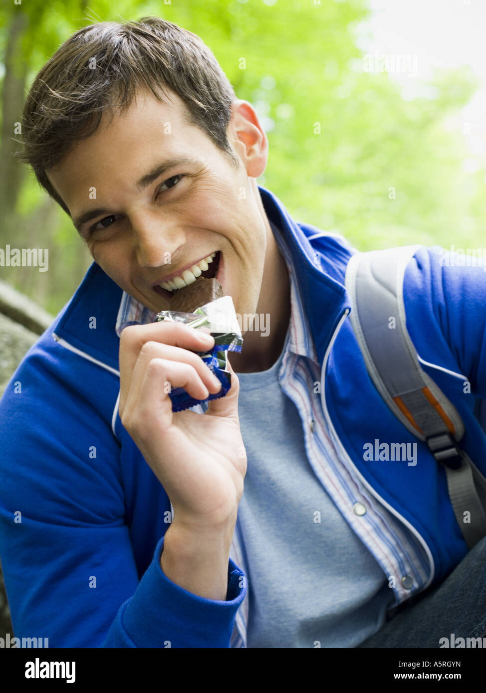 Close up of a young man eating a chocolate bar Stock Photo - Alamy