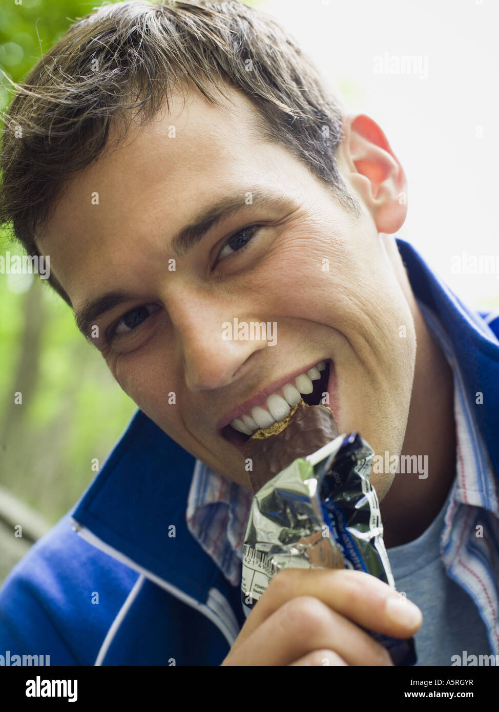 Close up of a young man eating a chocolate bar Stock Photo - Alamy