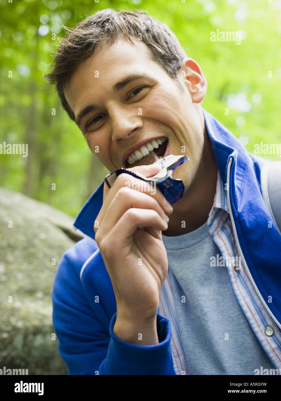 Close up of a young man eating a chocolate bar Stock Photo - Alamy