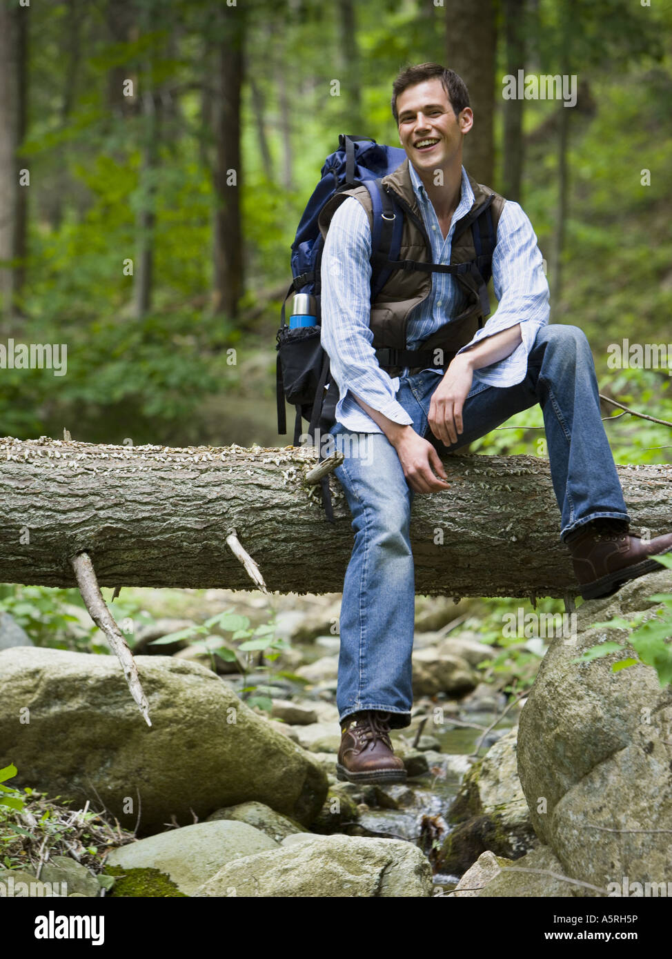 Portrait of a young man sitting on a fallen tree Stock Photo - Alamy