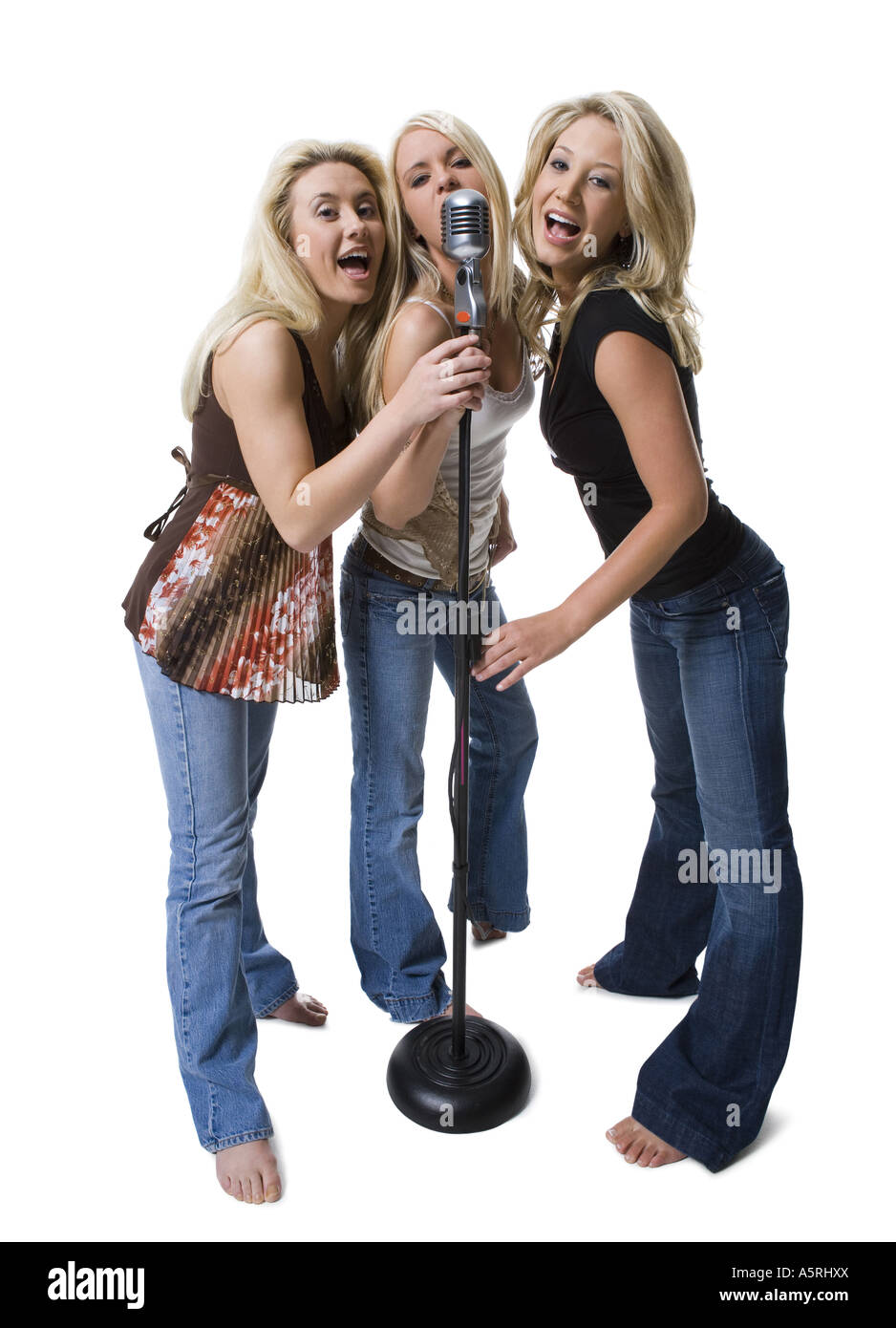 Portrait of three young women holding a microphone and singing Stock ...