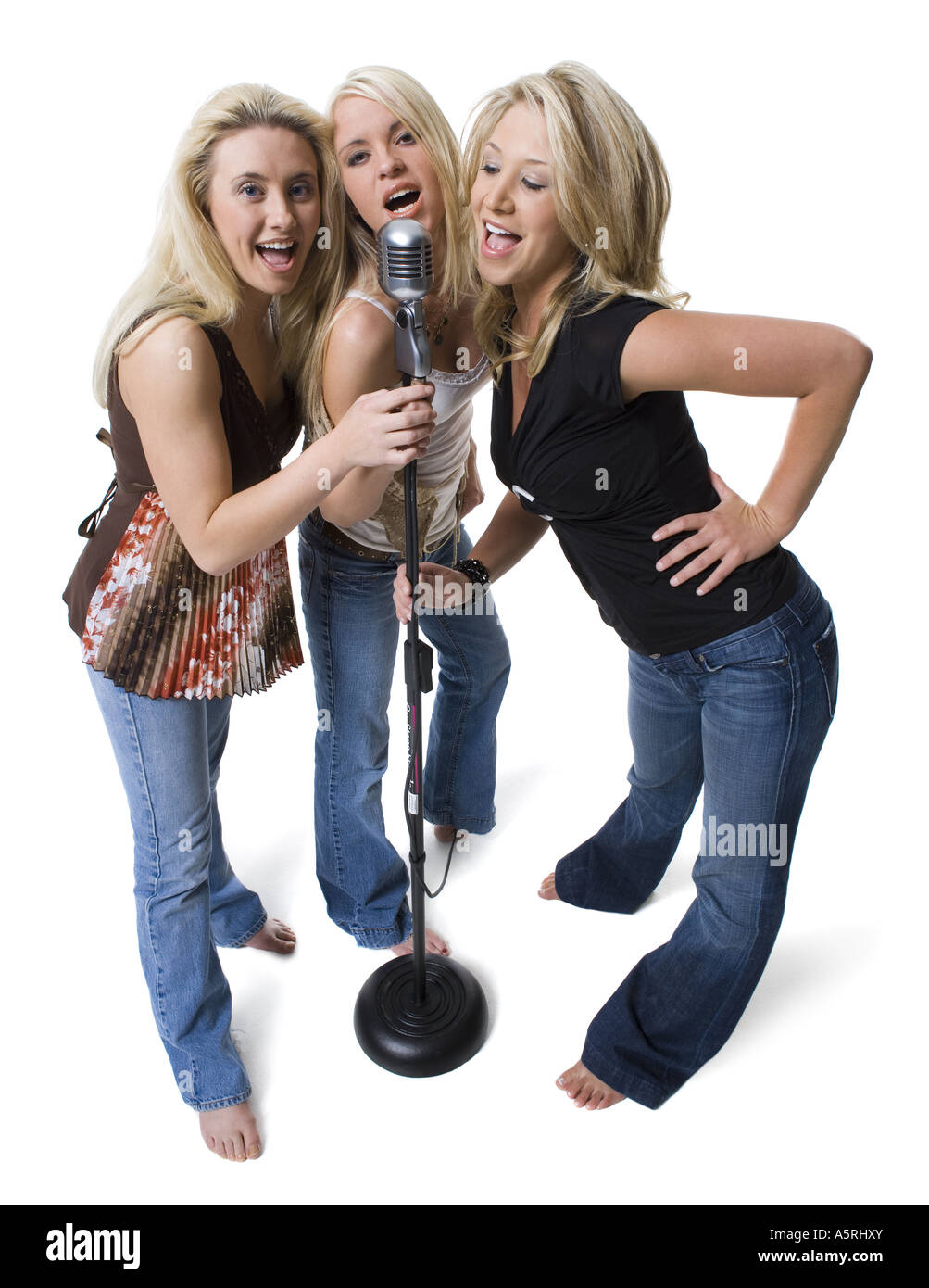 Portrait of three young women holding a microphone and singing Stock ...