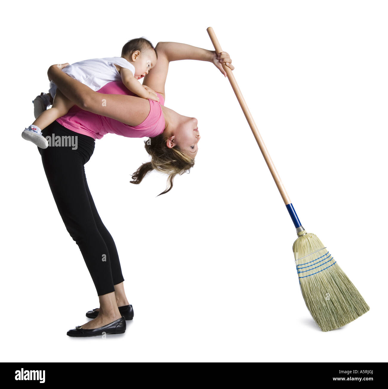 Contortionist mother sweeping while holding baby daughter Stock Photo ...