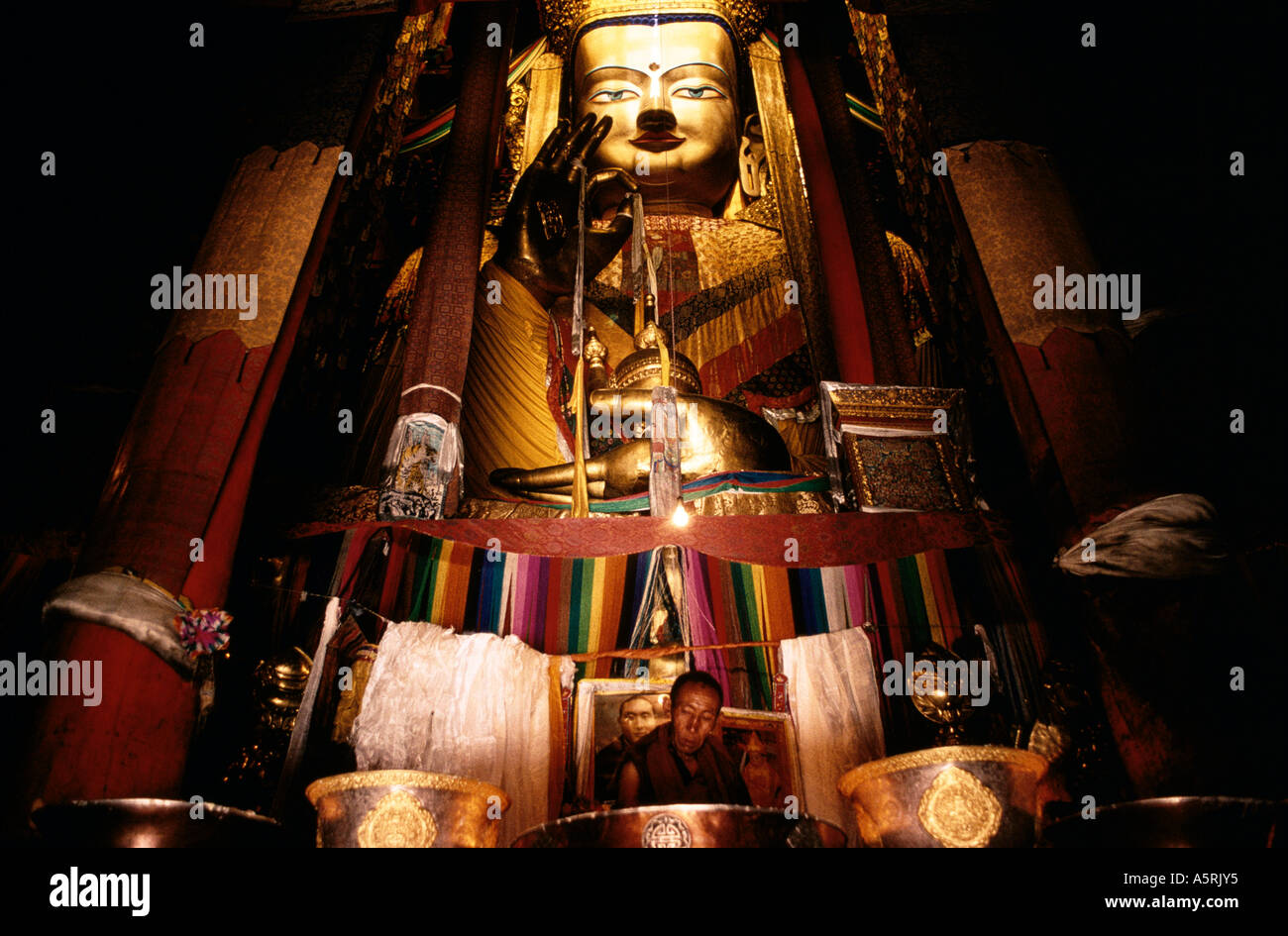 A MONK ATTENDS TO THE ALTAR UNDER THE WATCHFUL EYE OF THE MAITREYA THE ...