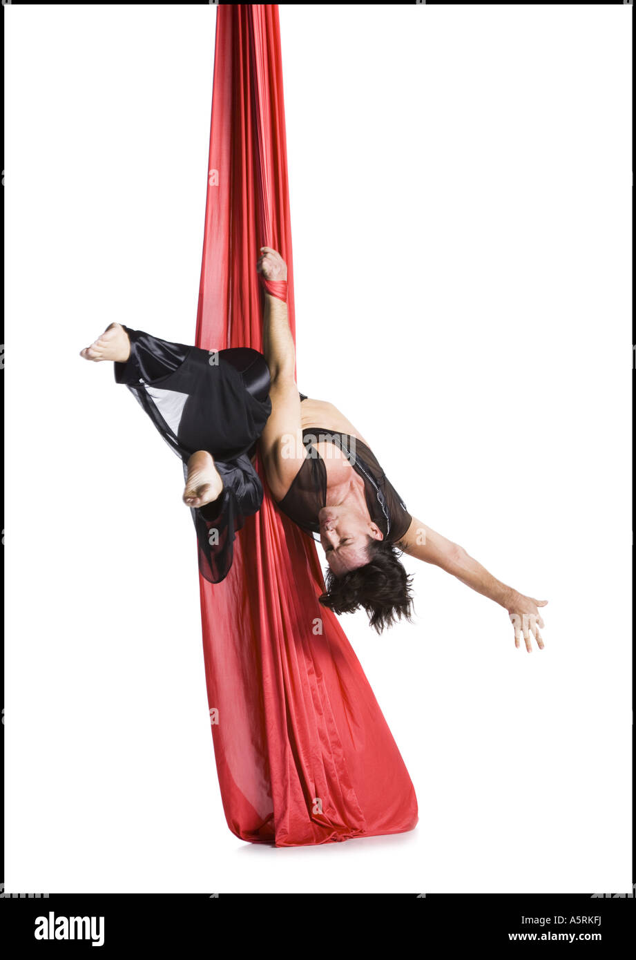 Male circus gymnast tangled in red drapes Stock Photo - Alamy