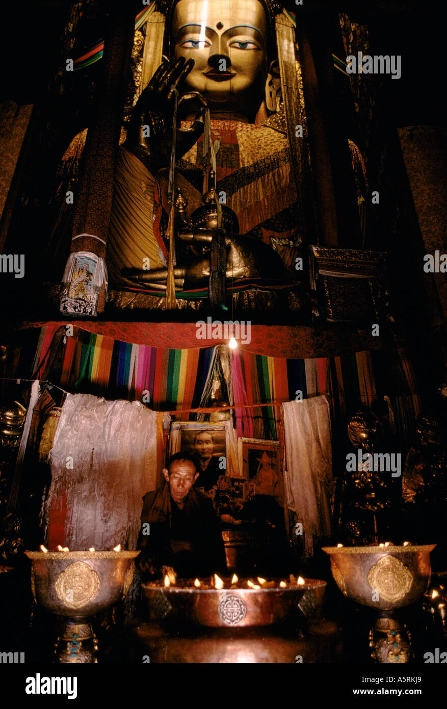 A MONK ATTENDS TO THE ALTAR UNDER THE WATCHFUL EYE OF THE MAITREYA THE ...