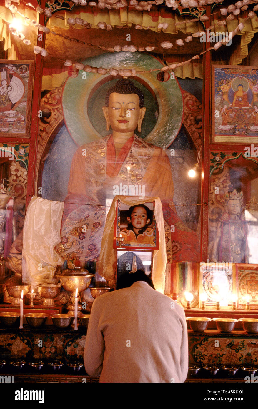 A MONK ATTENDS TO THE ALTAR UNDER THE WATCHFUL EYE OF THE MAITREYA THE ...