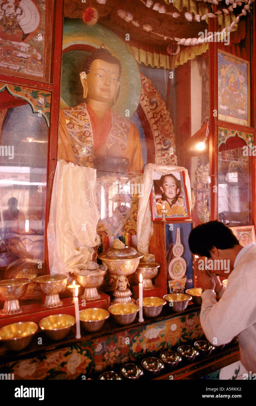 A MONK ATTENDS TO THE ALTAR UNDER THE WATCHFUL EYE OF THE MAITREYA THE ...