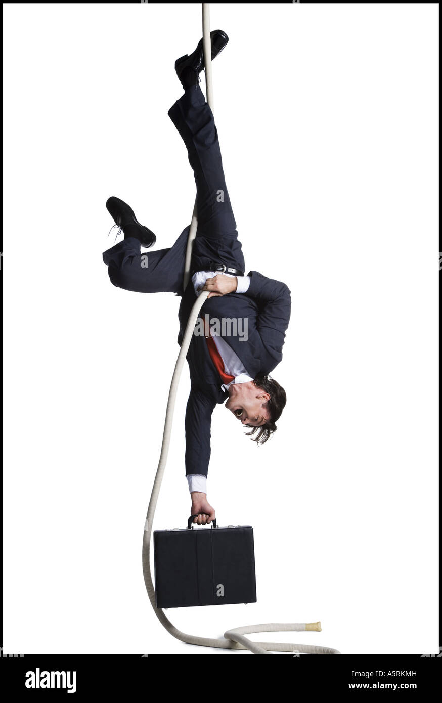 Businessman with briefcase dangling upside down from a rope Stock Photo ...