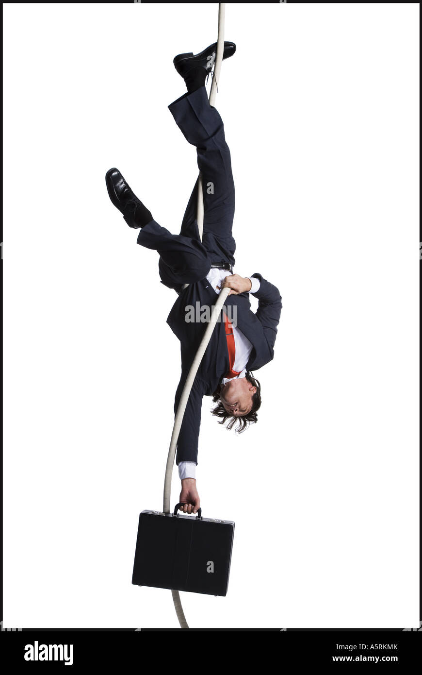 Businessman with briefcase dangling upside down from a rope Stock Photo ...