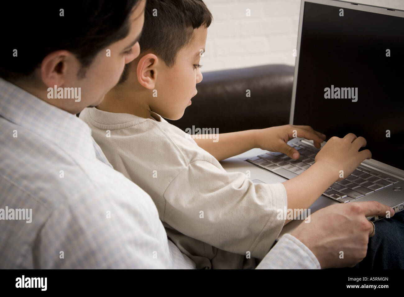 Father and young son working on laptop computer Stock Photo - Alamy