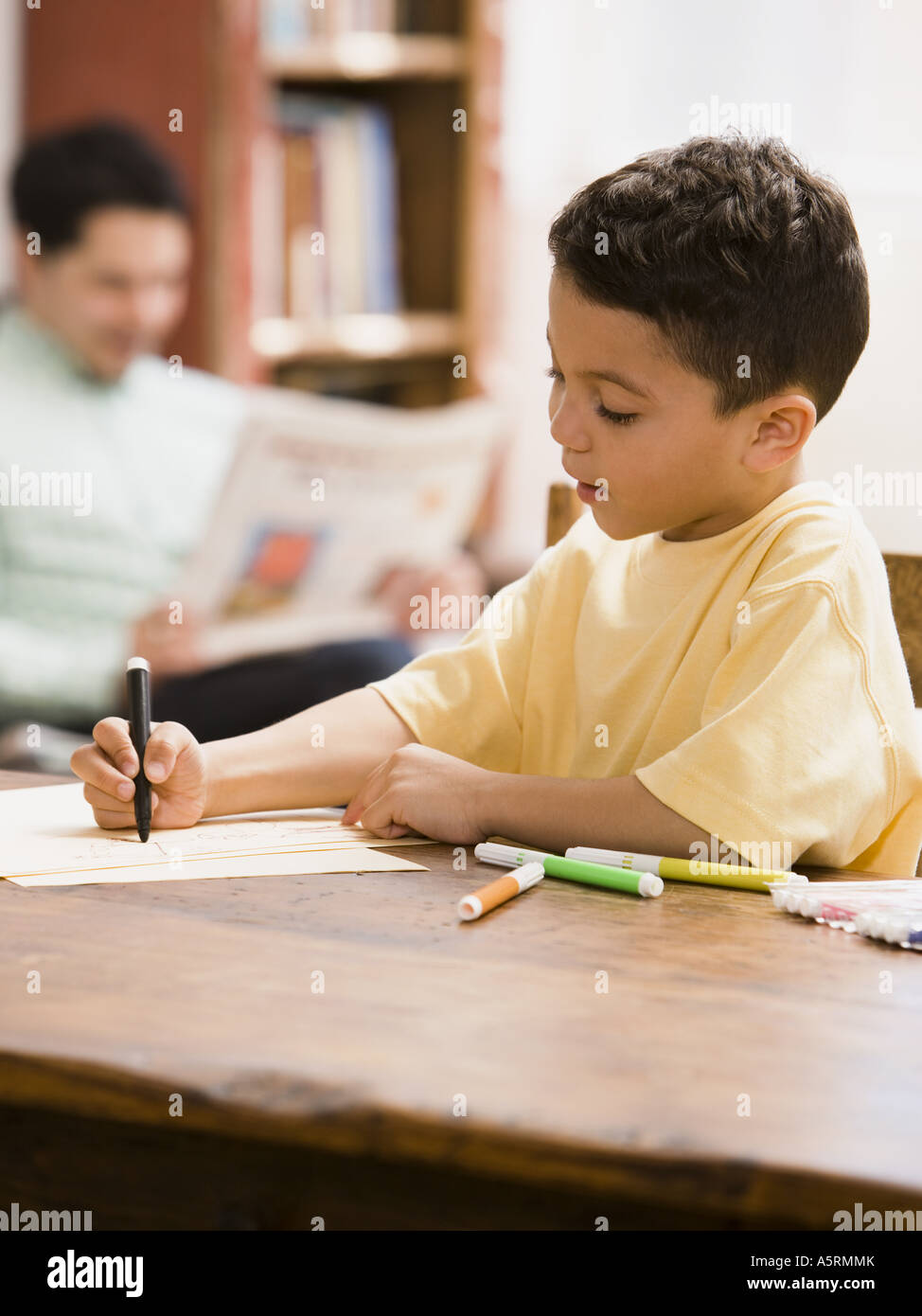 Young boy coloring and drawing with father supervising Stock Photo - Alamy