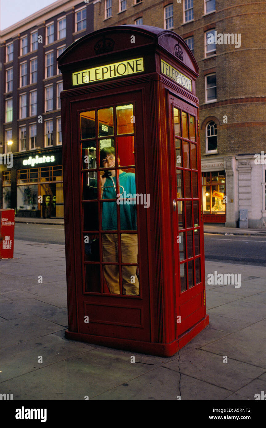 SMILING PERSON USING ILLUMINATED BRITISH TELECOM RED PUBLIC TELEPHONE ...