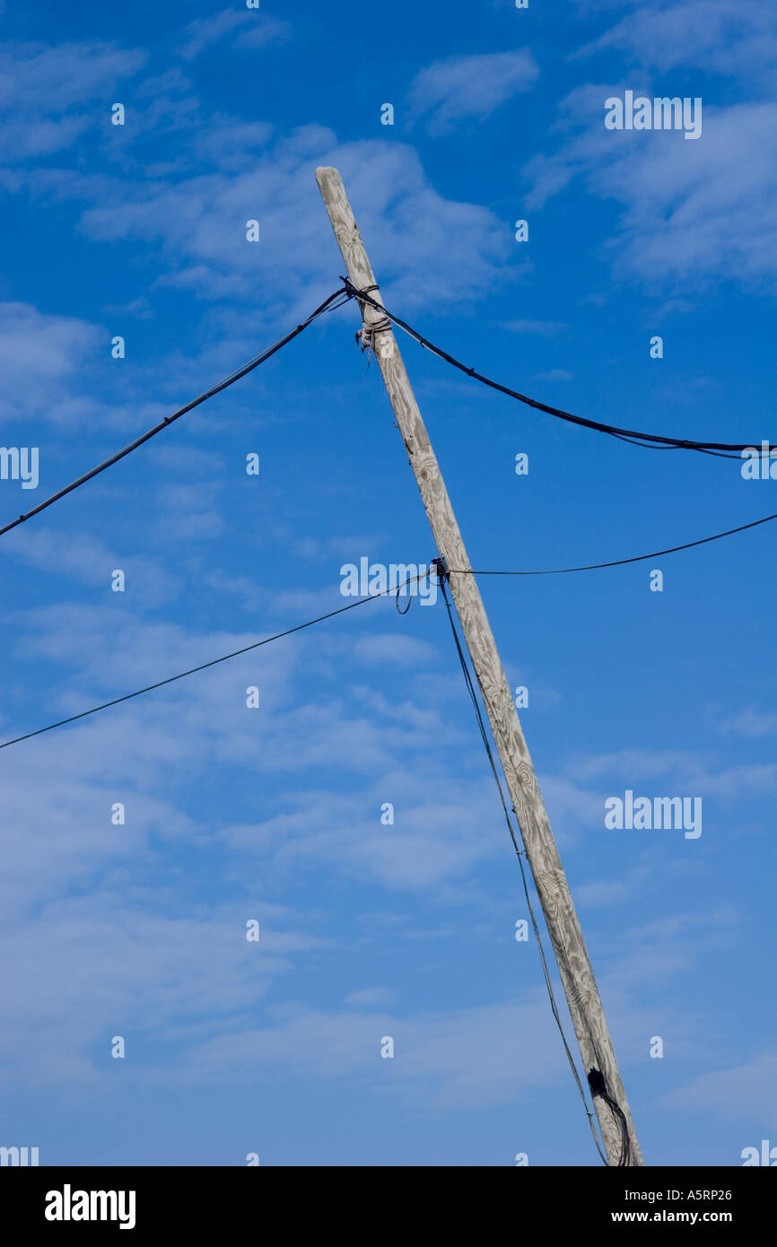 Leaning pole supporting electrical cable and telephone wire Stock Photo ...