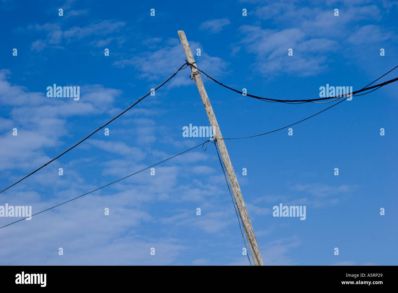 Leaning pole supporting electrical cable and telephone wire Stock Photo ...