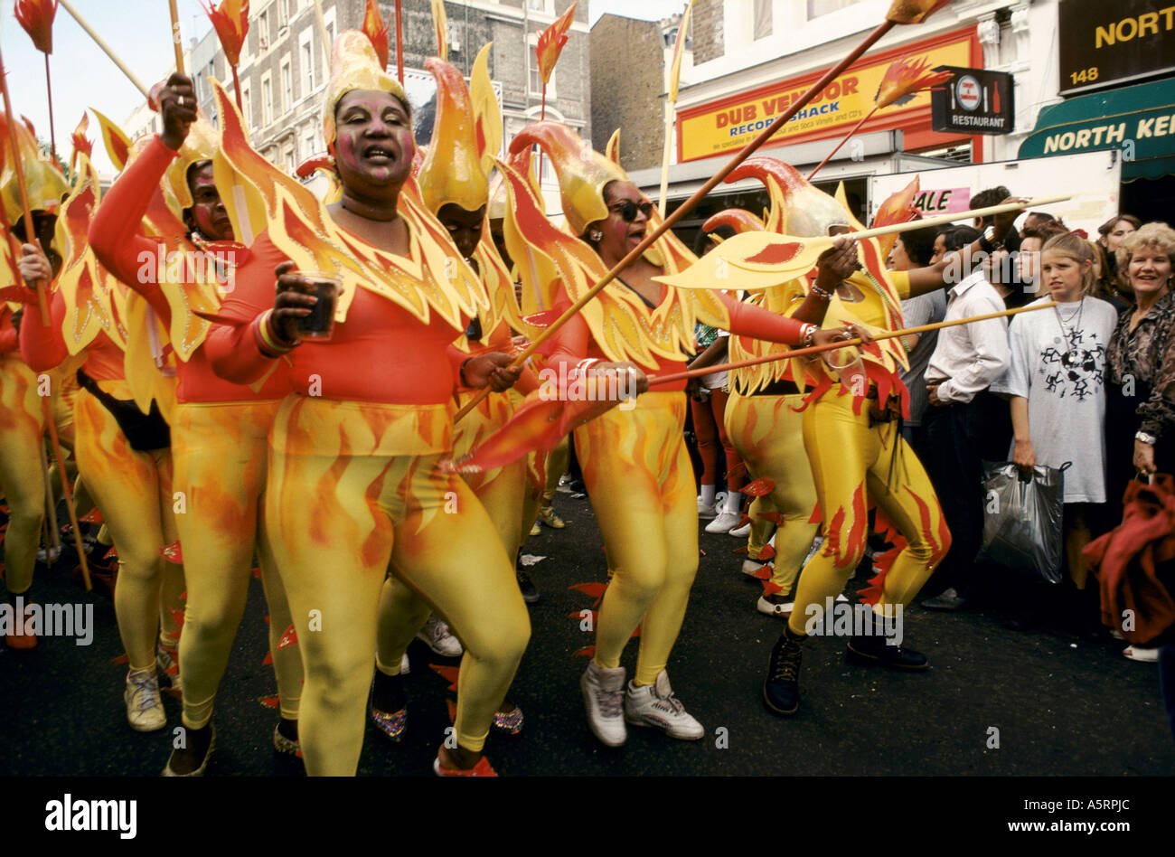 CROWD IN COSTUMES OF FLAME DANCING ON STREET IN NOTTING HILL CARNIVAL ...