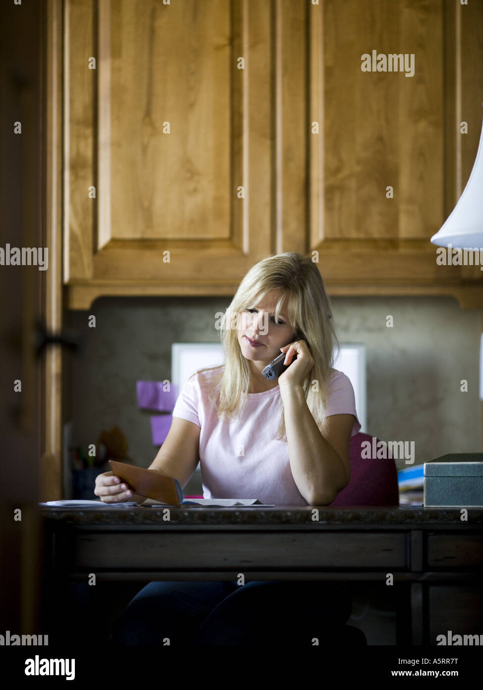 Woman paying bills over telephone Stock Photo - Alamy