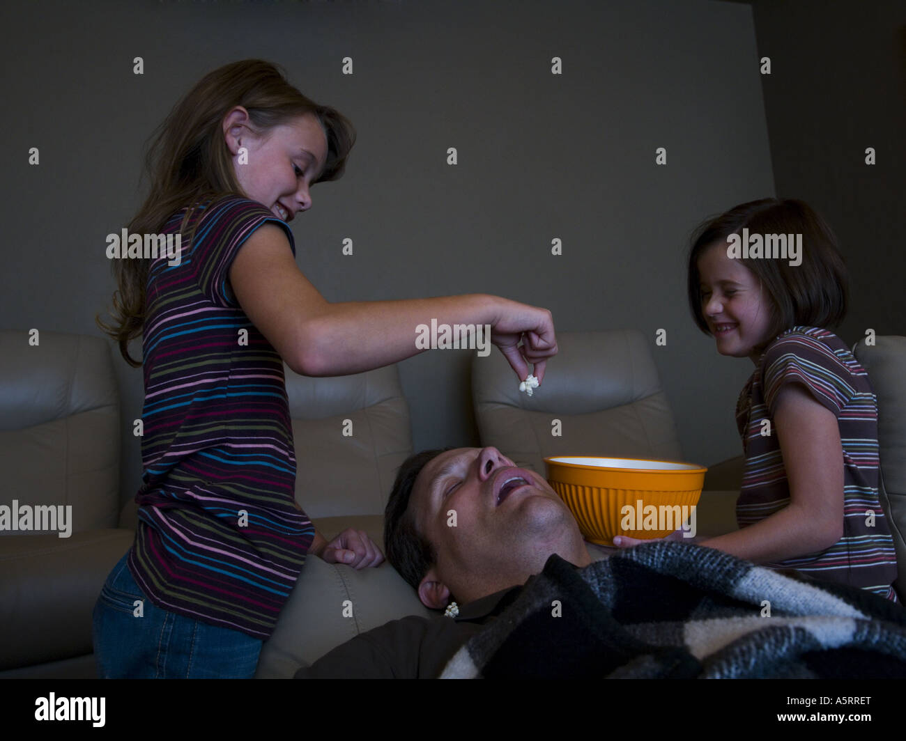Daughters dropping popcorn into sleeping father s mouth Stock Photo - Alamy