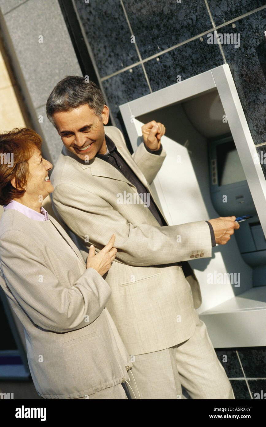 Mature couple standing at ATM machine Stock Photo - Alamy