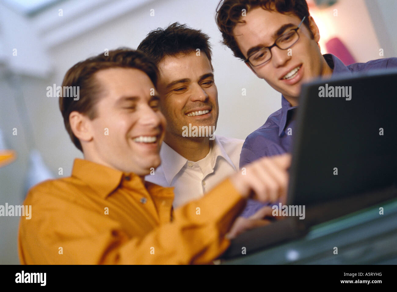 Three young men using laptop together Stock Photo - Alamy