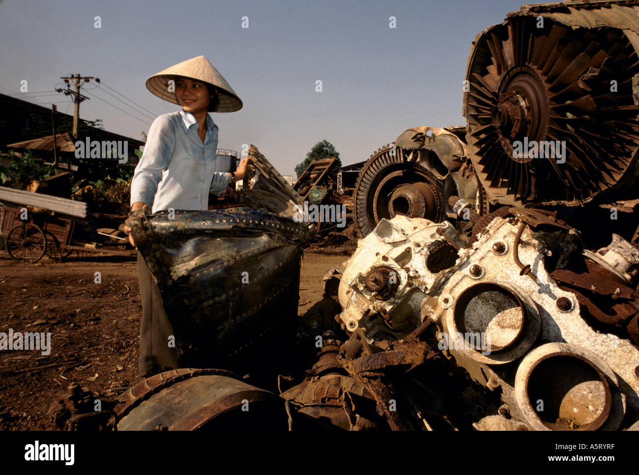 VIETNAM, A YOUNG WOMAN WITH CONICAL HAT HOLDING A PIECE OF SCRAP METAL ...