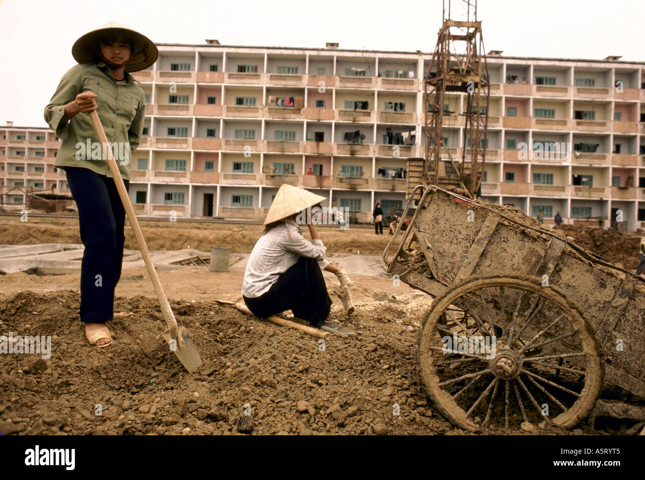 VIETNAM, FEMALE BUILDERS WITH CONICAL HATS AT REST ON A BUILDING SITE ...