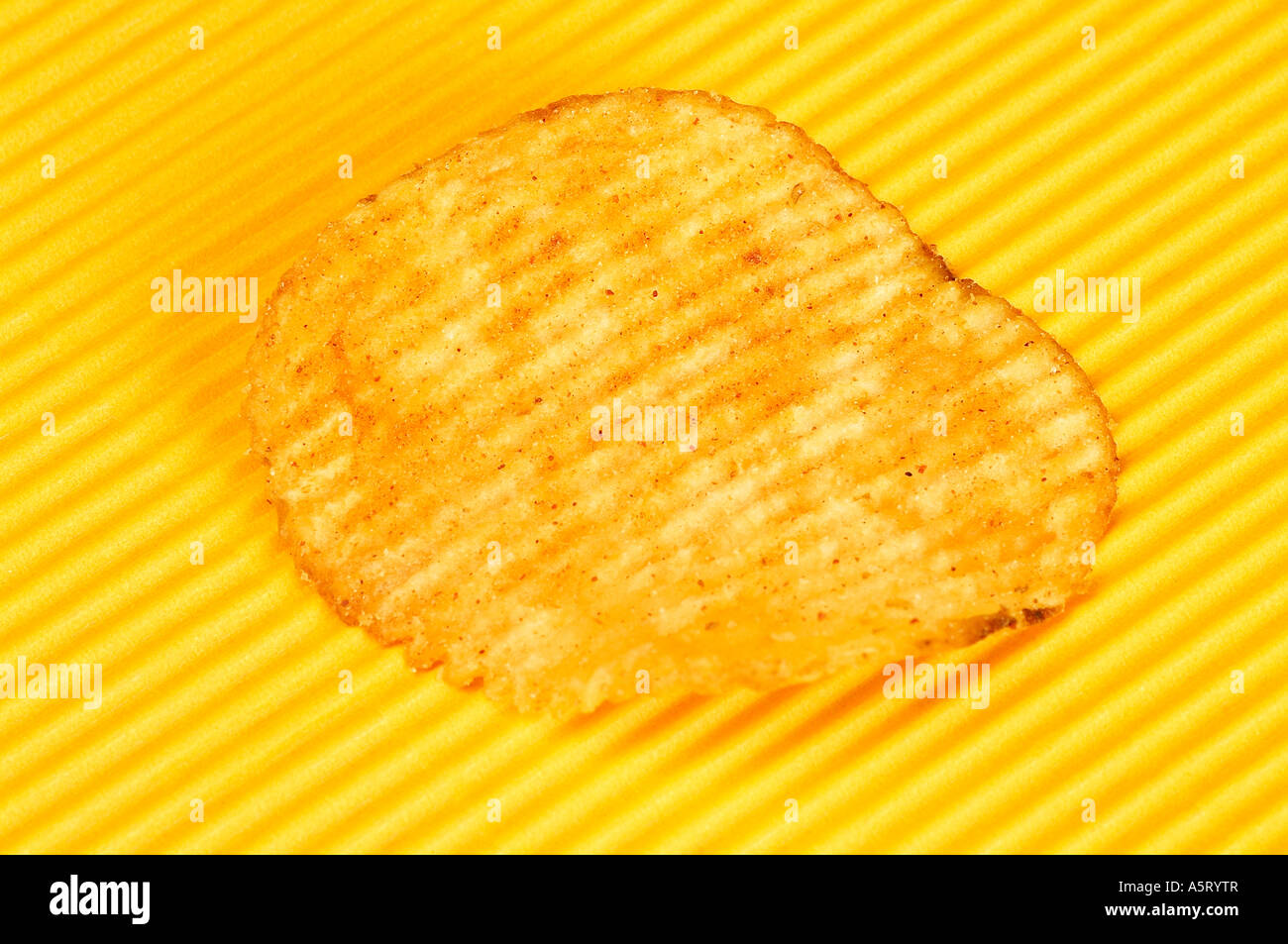 Flake of crisps on yellow, stripped background Stock Photo - Alamy