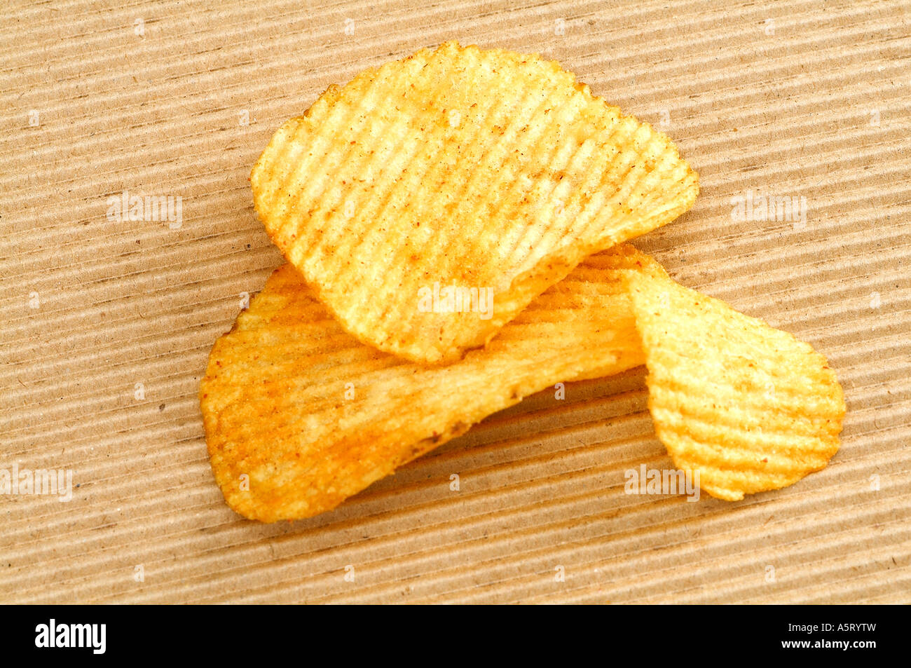 Flake of crisps on light brown, stripped background Stock Photo - Alamy