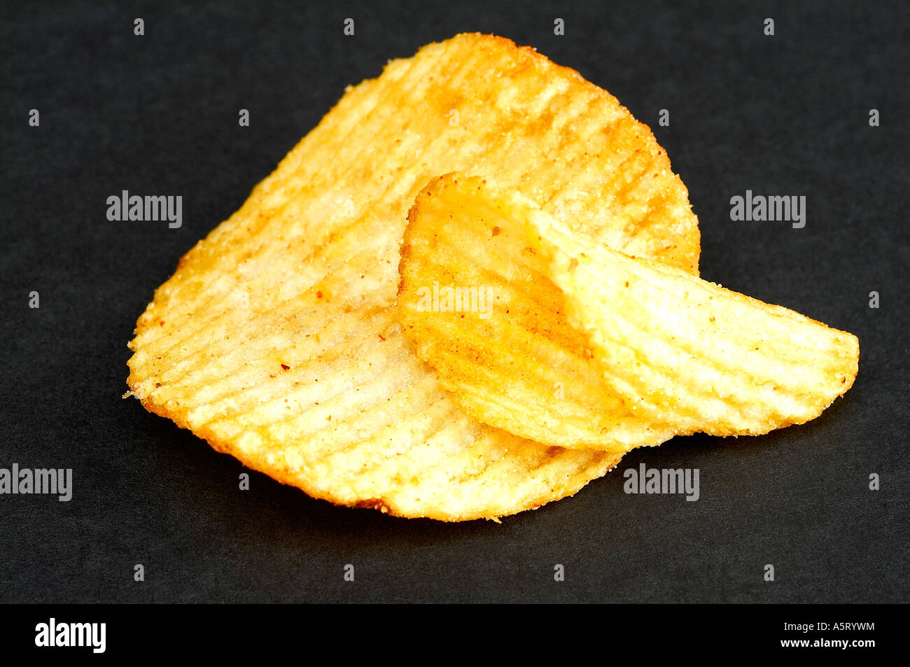 Flakes of crisps on black background Stock Photo - Alamy