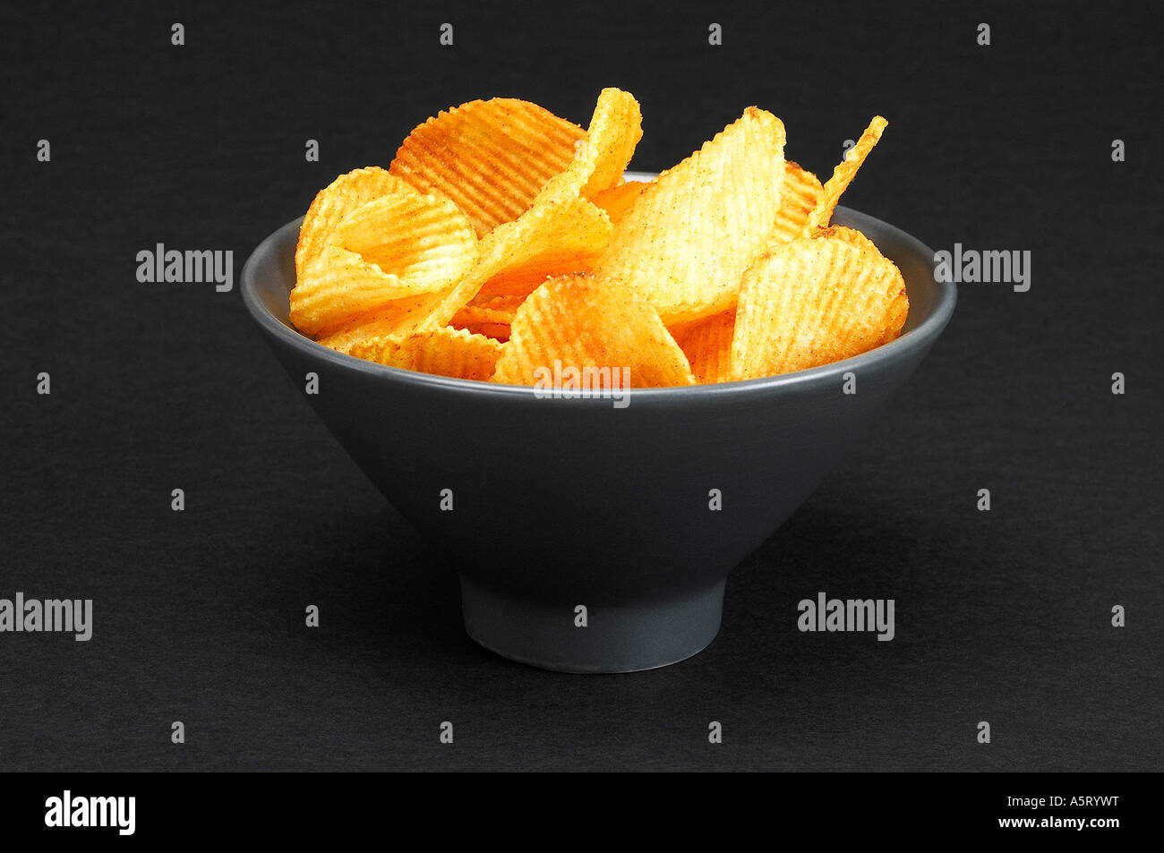 Bowl of crisps on black background Stock Photo - Alamy